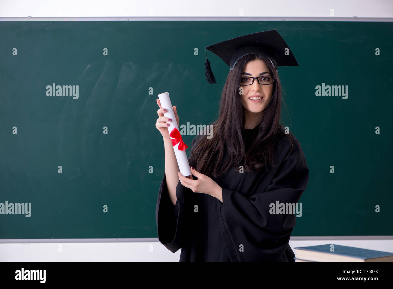 Female graduate student in front of green board Stock Photo - Alamy