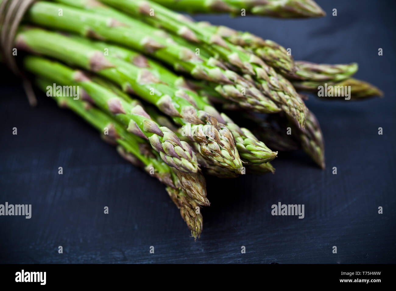 Bunch of fresh raw garden asparagus closeup on black board background ...