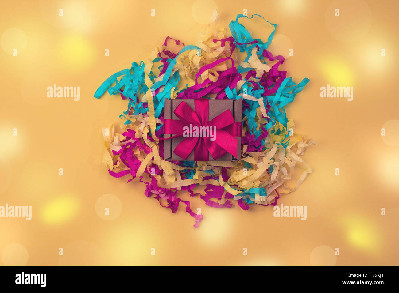Gift box with colored streamers bright yellow background. A top view of ...