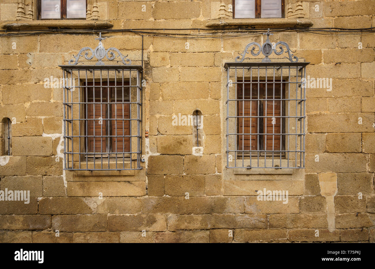 Window with bars on a stone facade in old medieval town of Plasencia ...