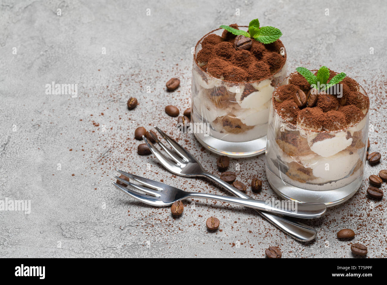 two portions Classic tiramisu dessert in a glass on concrete background ...
