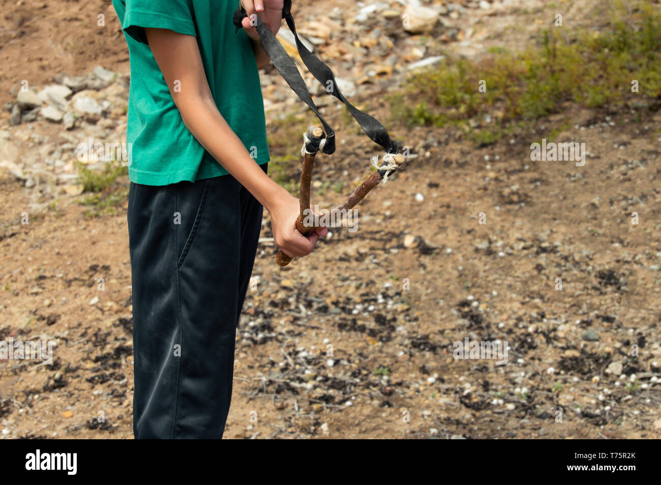 Little kid using handmade slingshot made with tree branch and recycled ...
