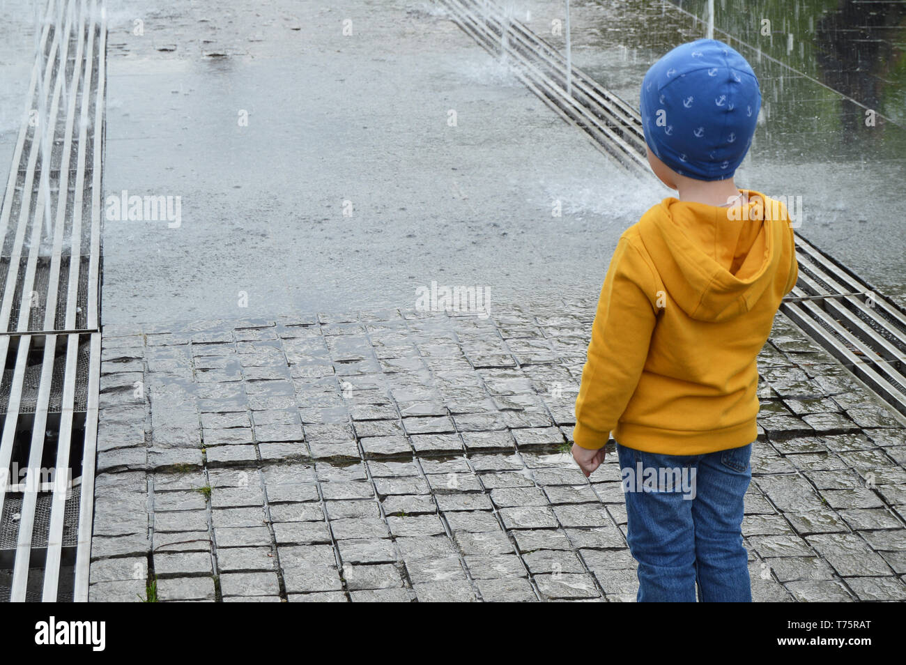 child standing near a puddle in the Park near the fountain, watching ...