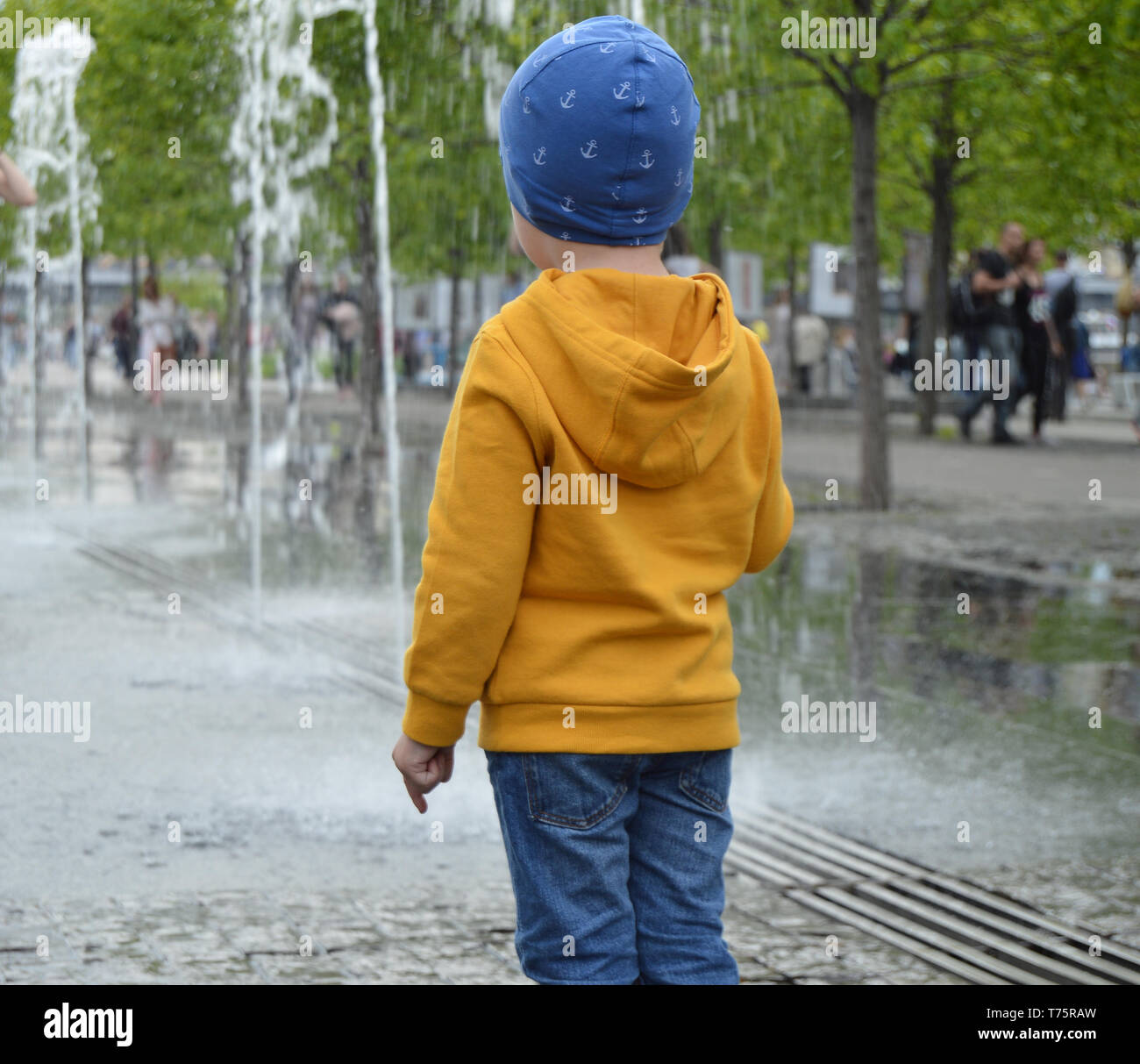child standing near a puddle in the Park near the fountain, watching ...