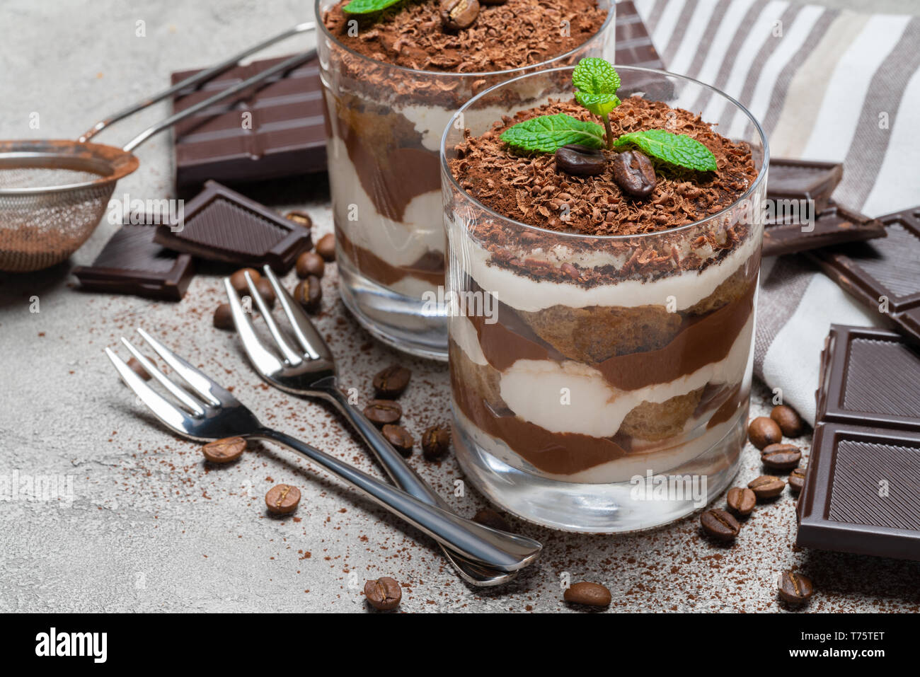 two portions Classic tiramisu dessert in a glass and chocolate bar on ...