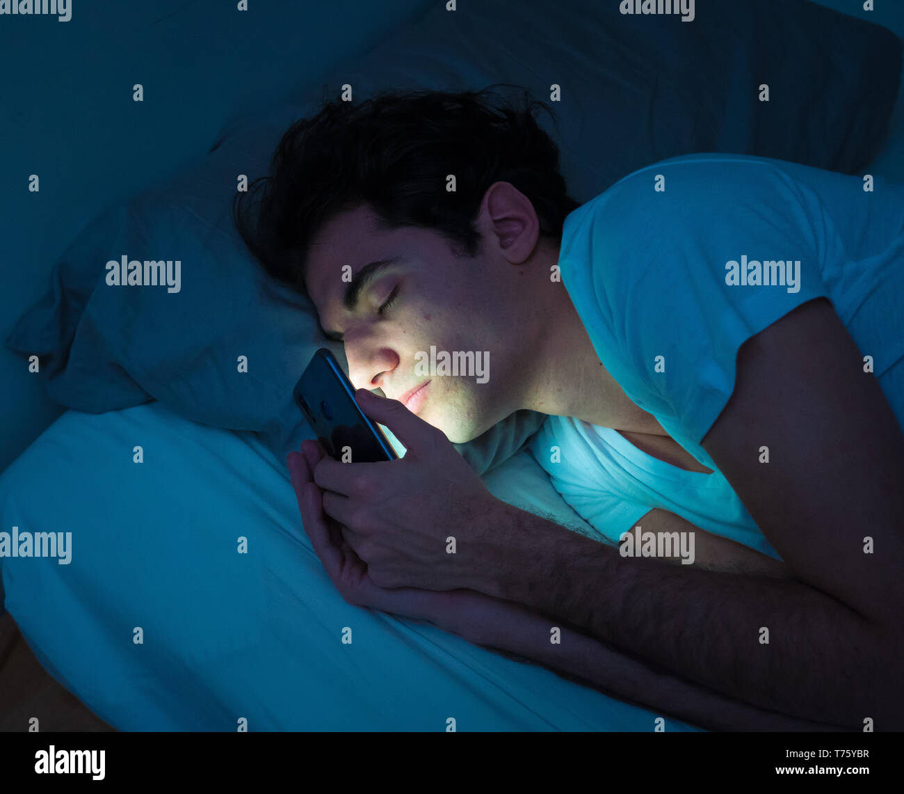 Addicted to social media young man falling asleep with smart mobile ...