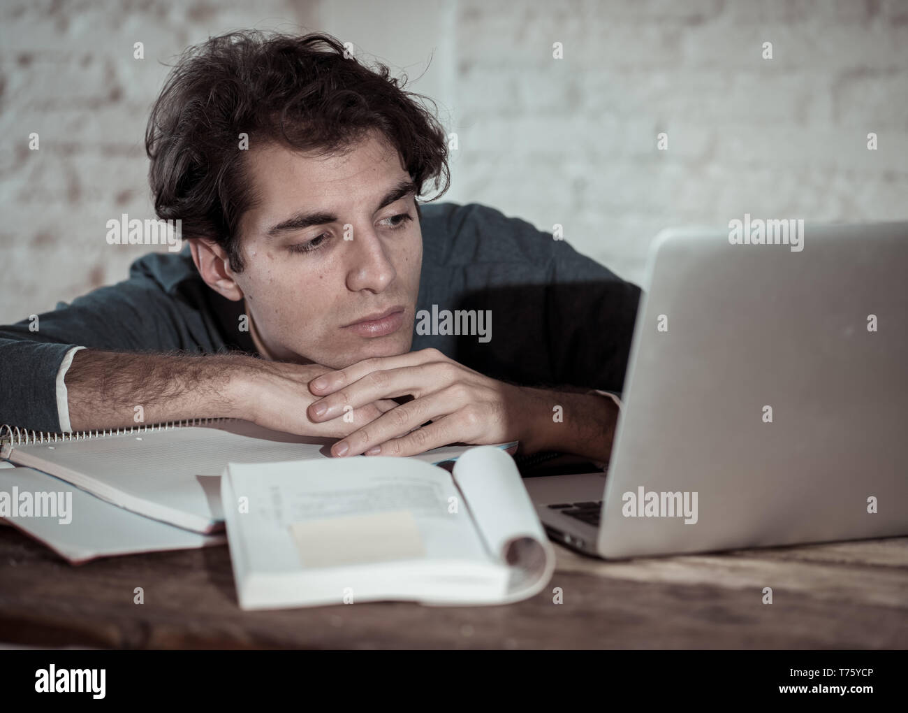 Overworked and tired male student working late at night on laptop ...