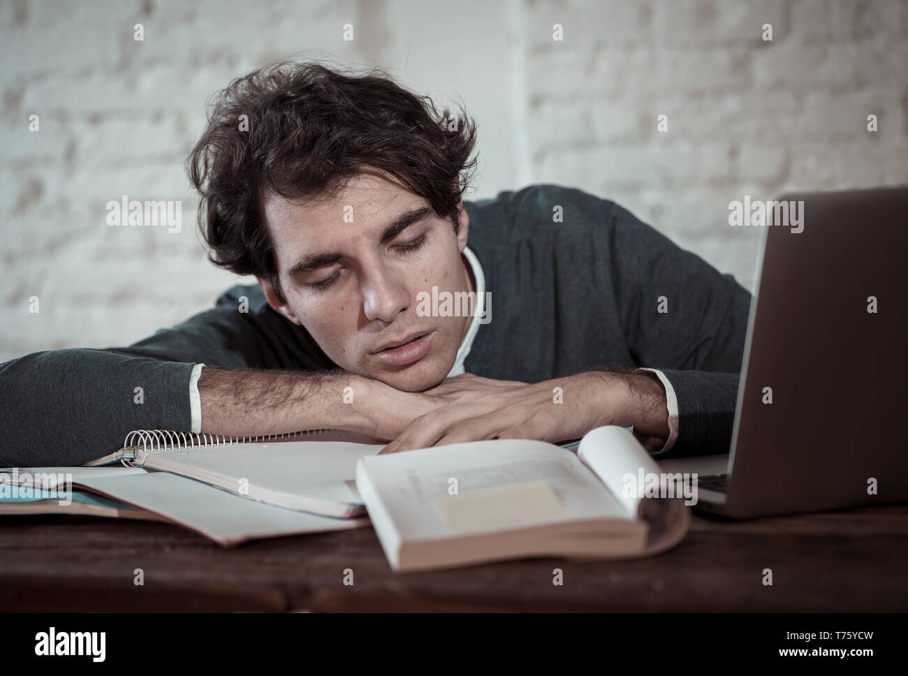 Overworked and tired male student working late at night on laptop ...