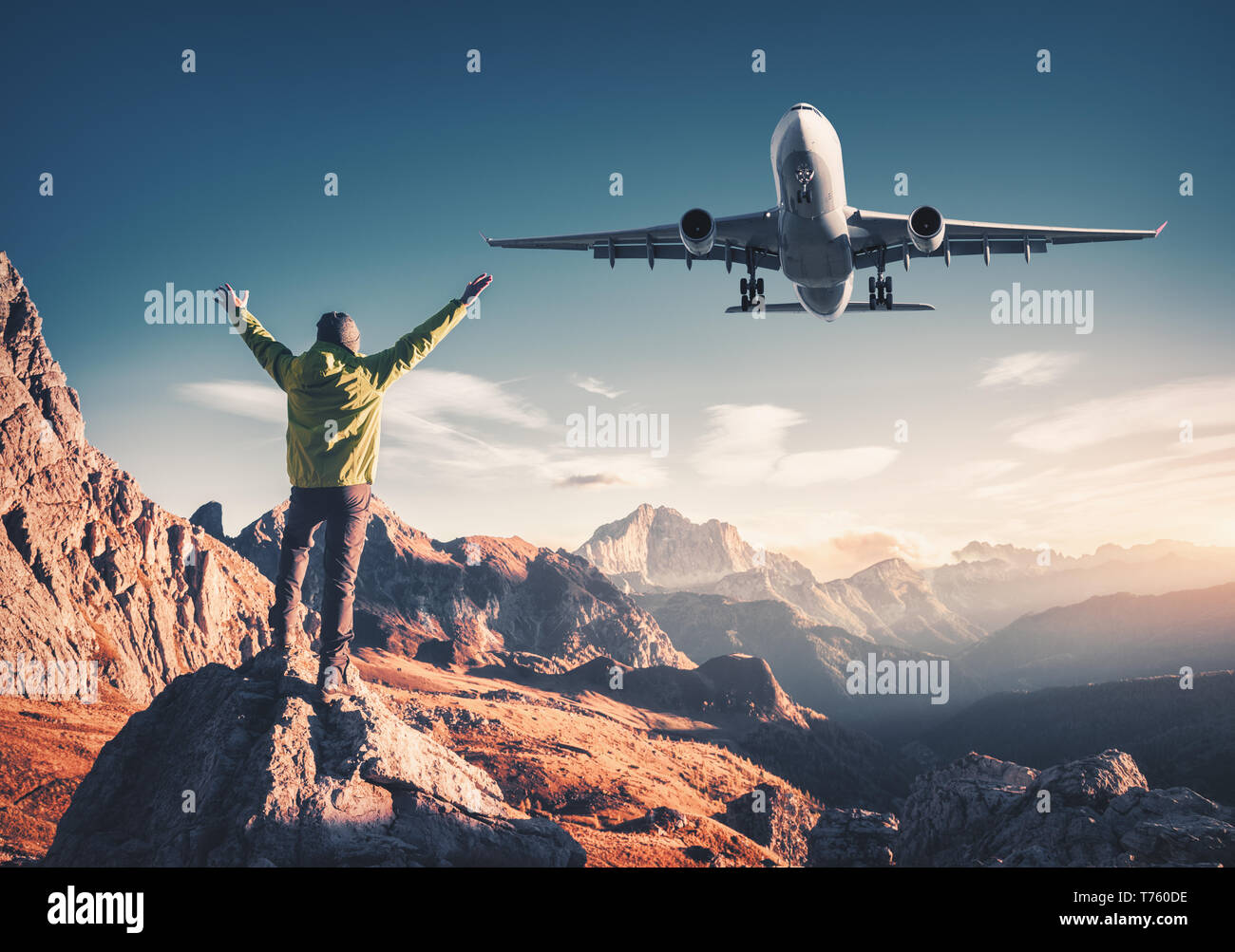 Airplane and man on the stone with raised up arms against mountains at ...