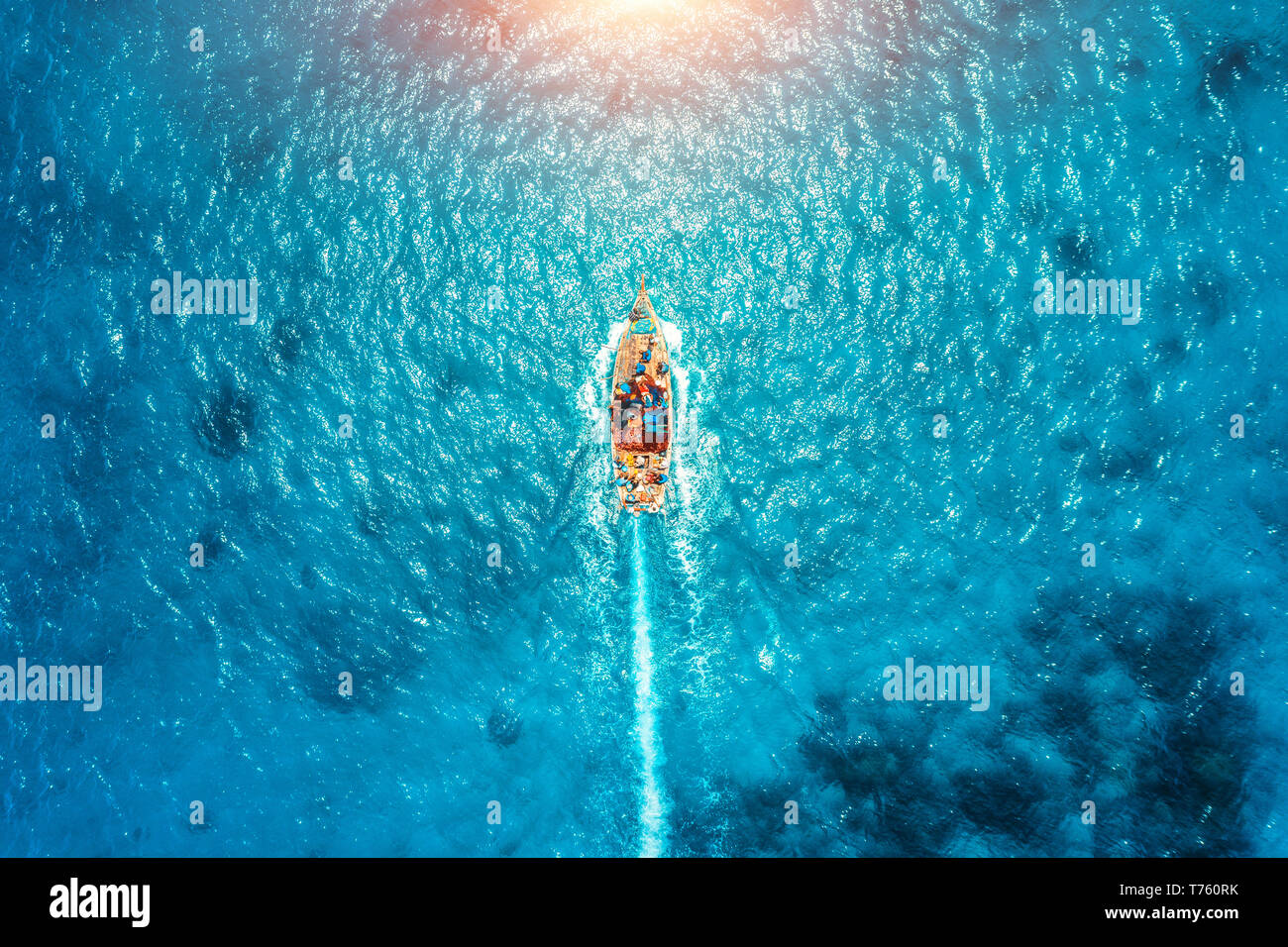 Aerial view of the fishing boat in transparent blue water at sunset in ...