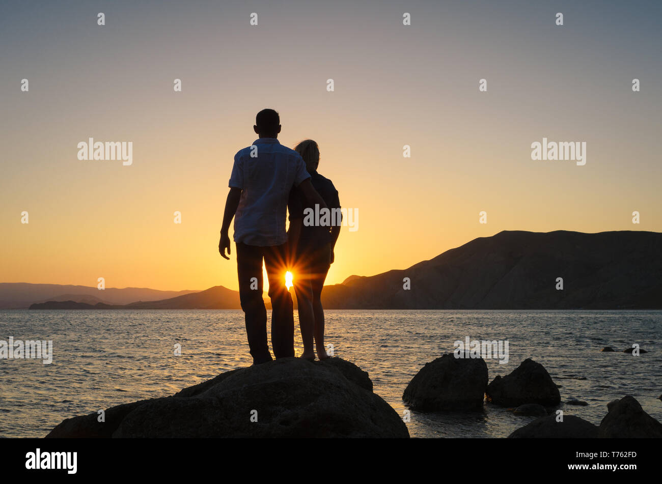 Honeymoon at a seaside resort. A couple is hugging and watching a ...