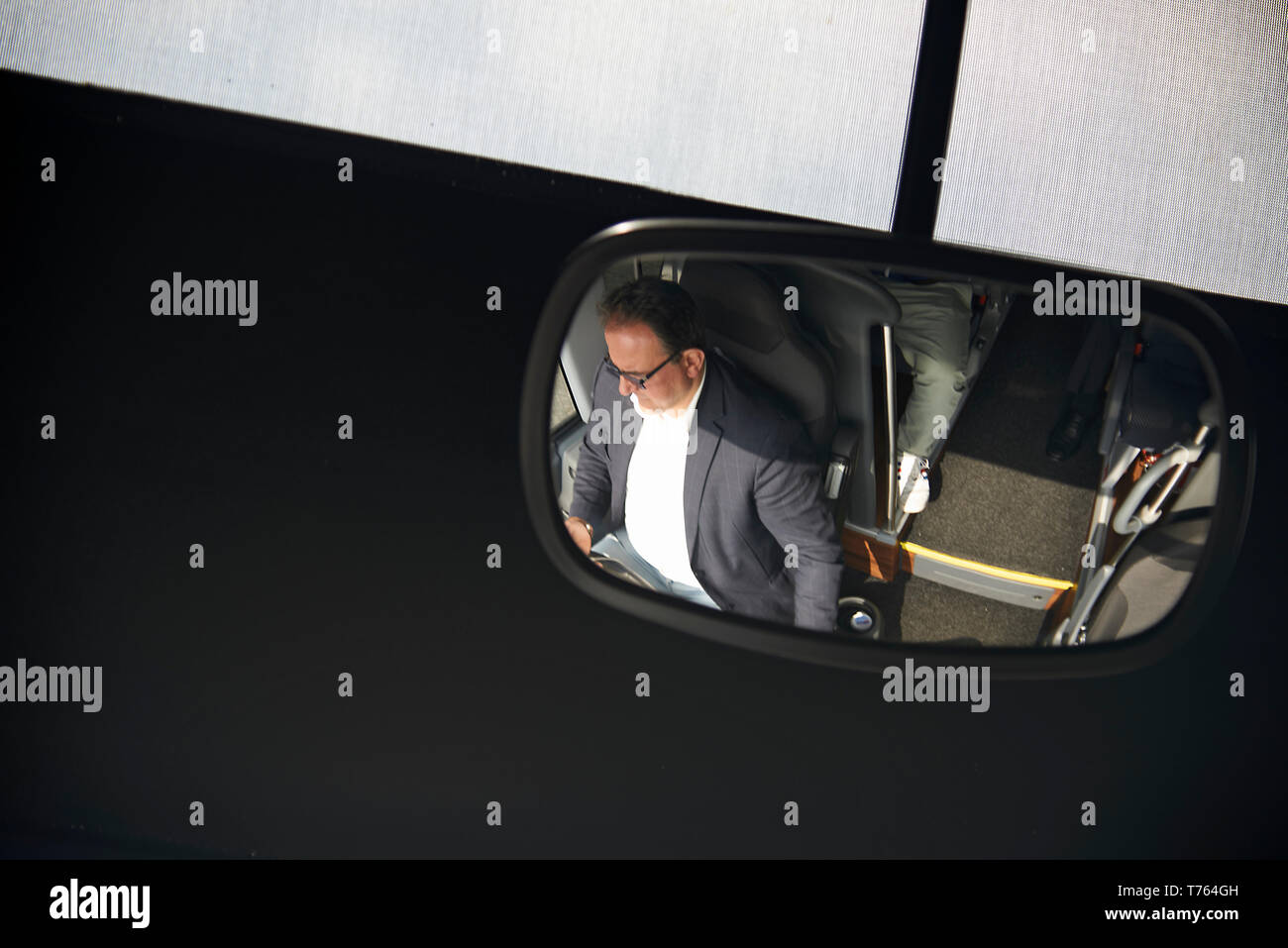 Close up of a rearview mirror on a bus showing the bus driver at the ...