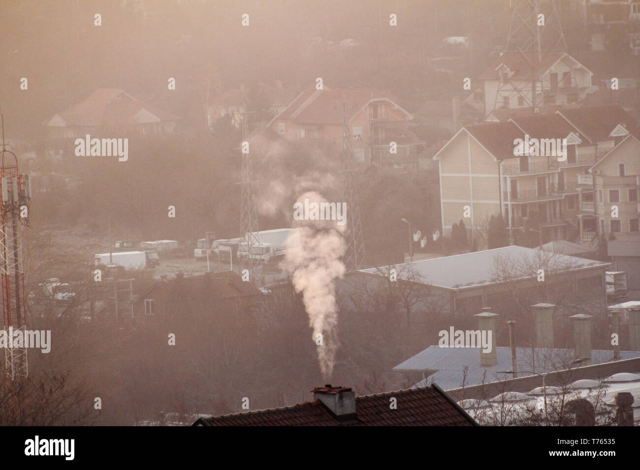 Smoking chimneys at roofs of houses emits smoke, smog at sunrise ...