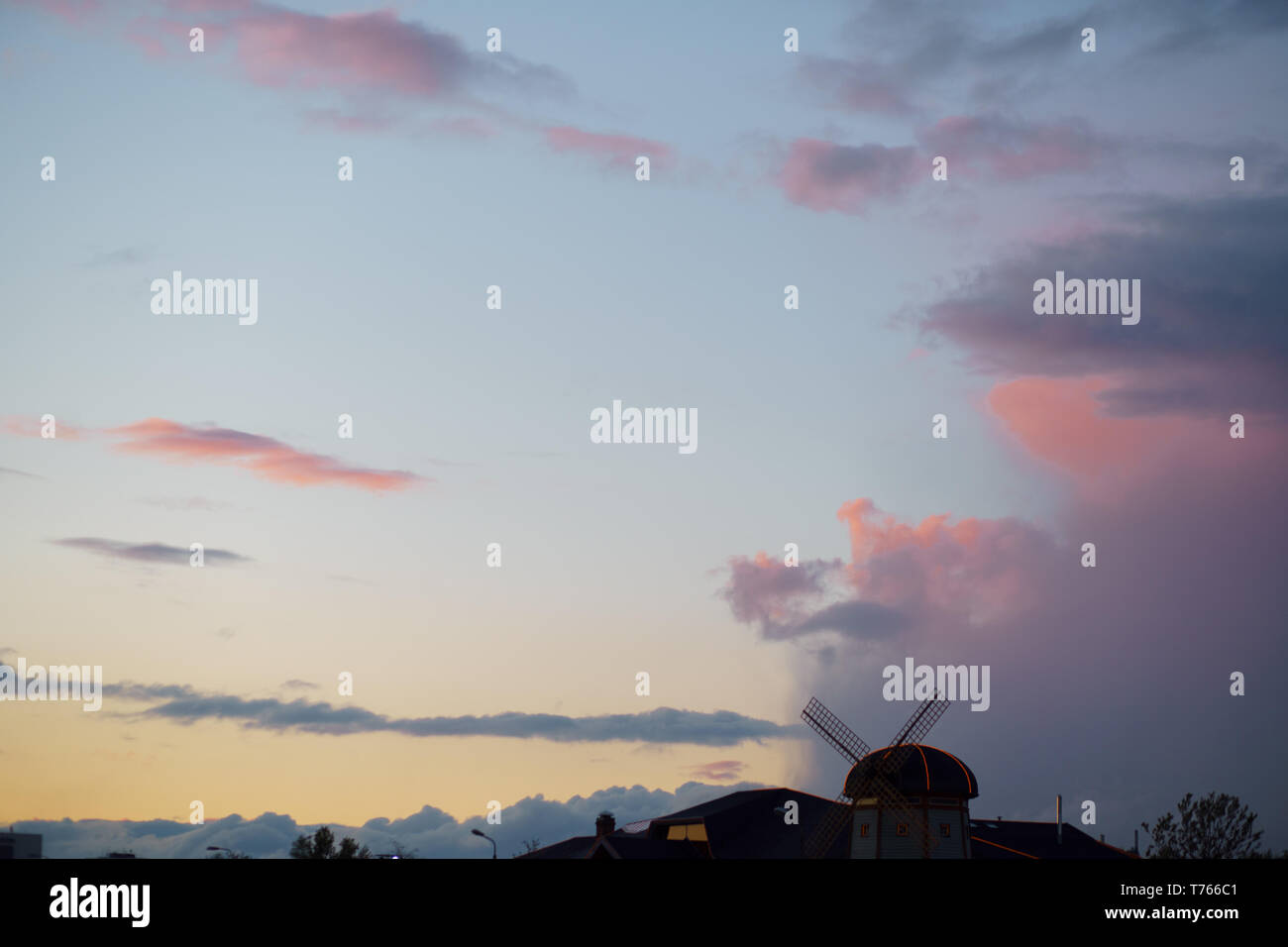 Pink vivid sunset with a mill in the background - Rainy clouds taking ...