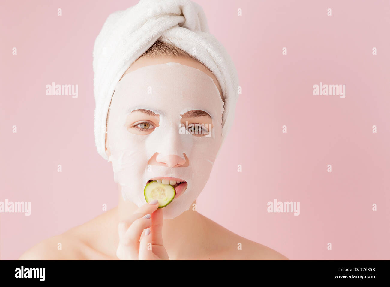 Beautiful young woman is applying a cosmetic tissue mask on a face on a ...