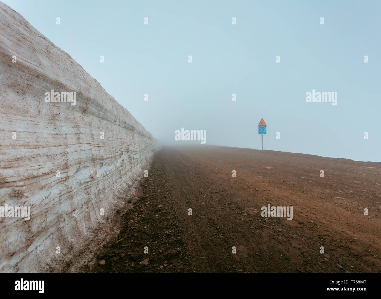 A foggy muddy road next to a wall and road signs Stock Photo - Alamy