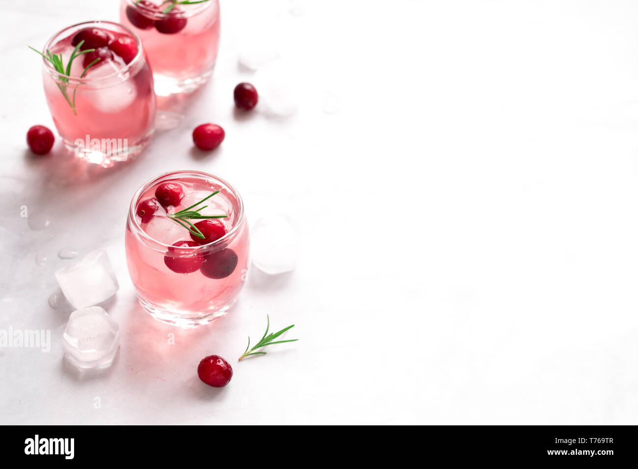 Cranberry Vodka Cocktail with ice cubes and rosemary on white marble ...