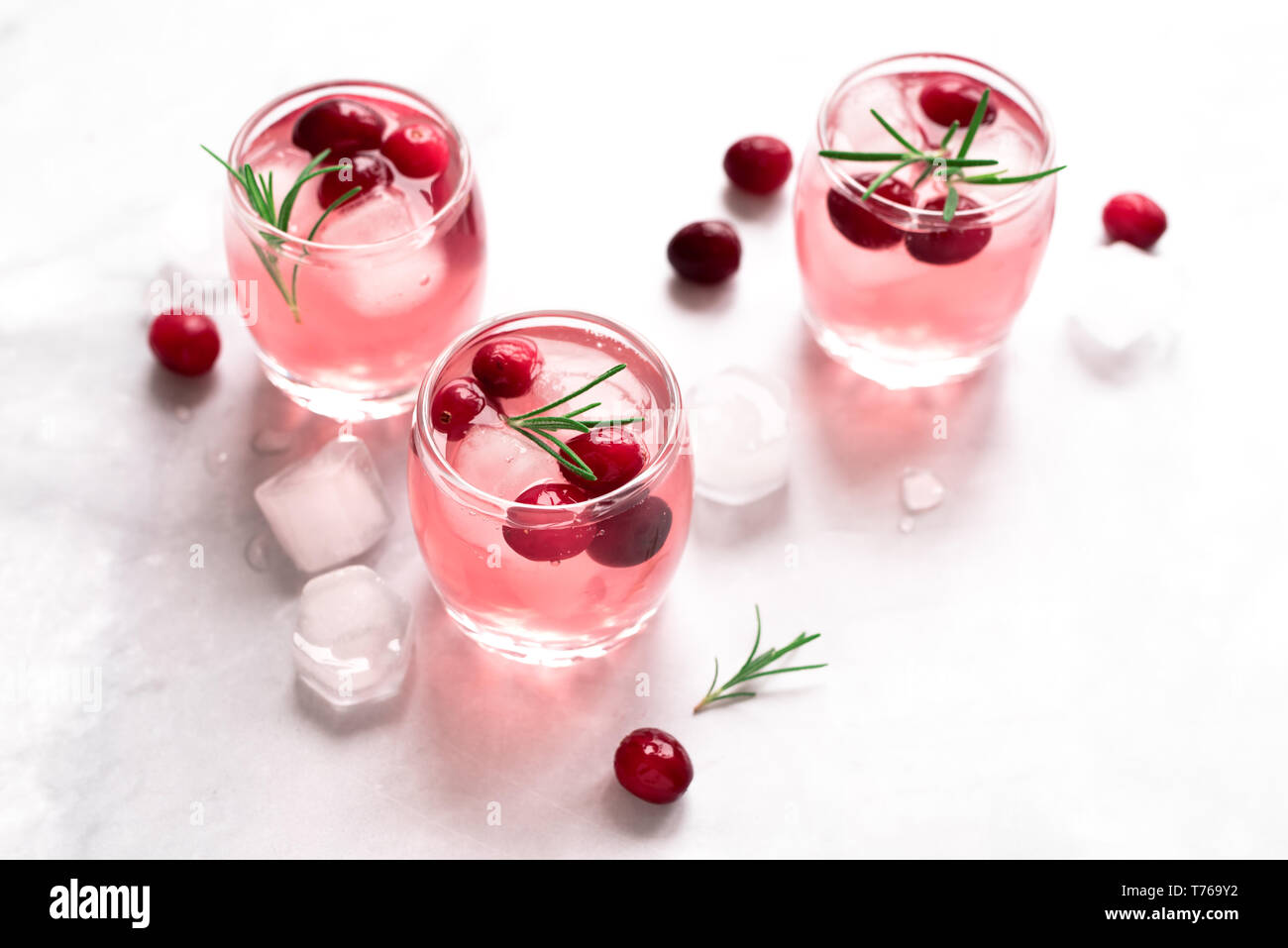 Cranberry Vodka Cocktail with ice cubes and rosemary on white marble ...