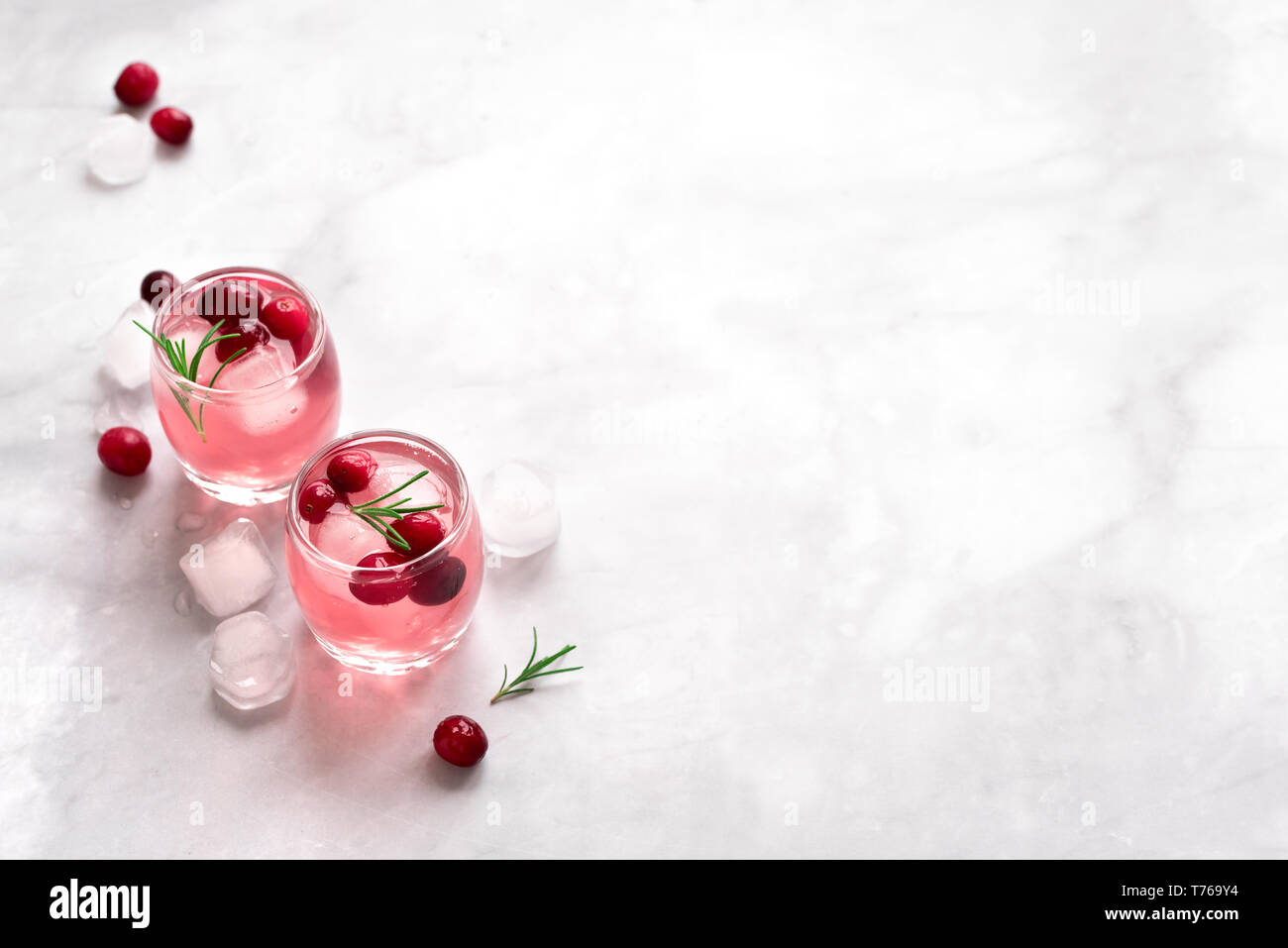 Cranberry Vodka Cocktail with ice cubes and rosemary on white marble ...