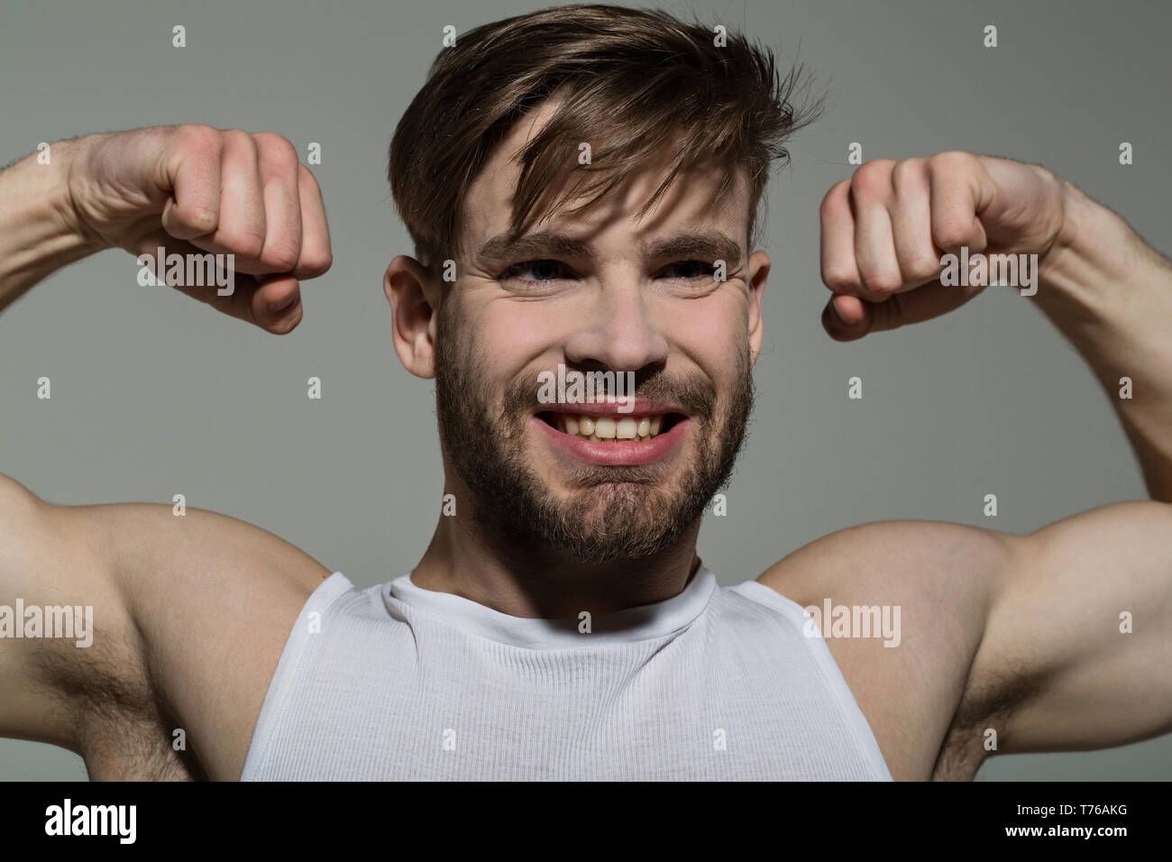 Macho smile with strong arms in white singlet Stock Photo - Alamy