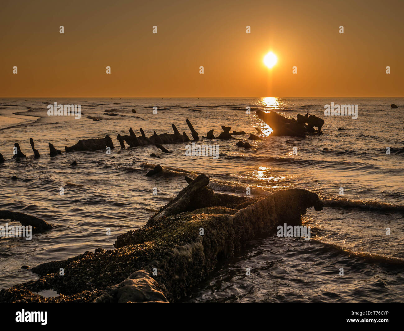 Sunset with a sunken shipwreck from World War II close to the beach ...