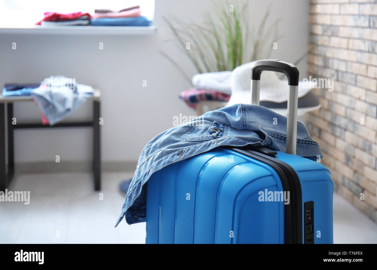 Packed suitcase and denim jacket in room Stock Photo - Alamy
