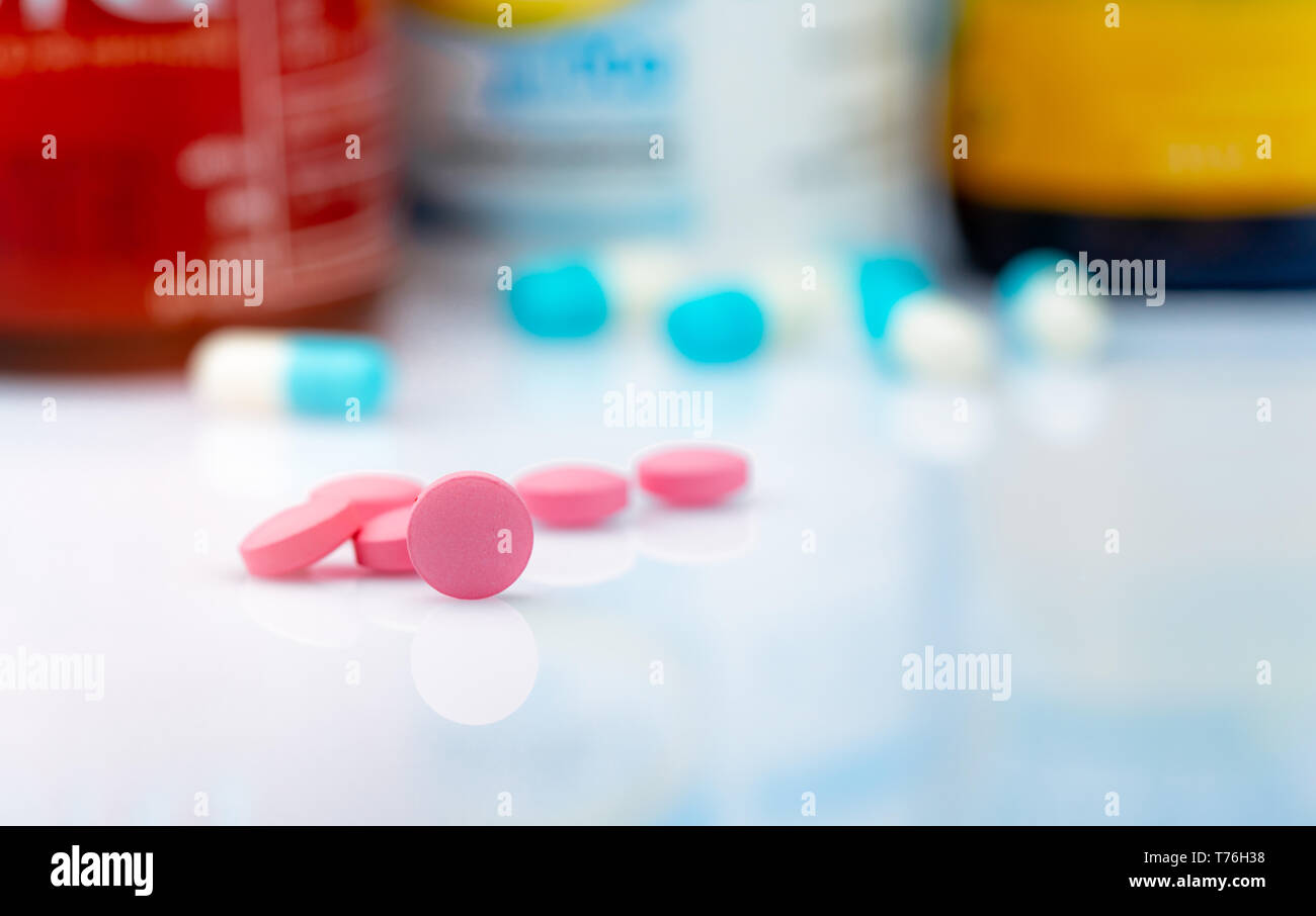Round pink tablets pill on blurred background of drug bottle ...