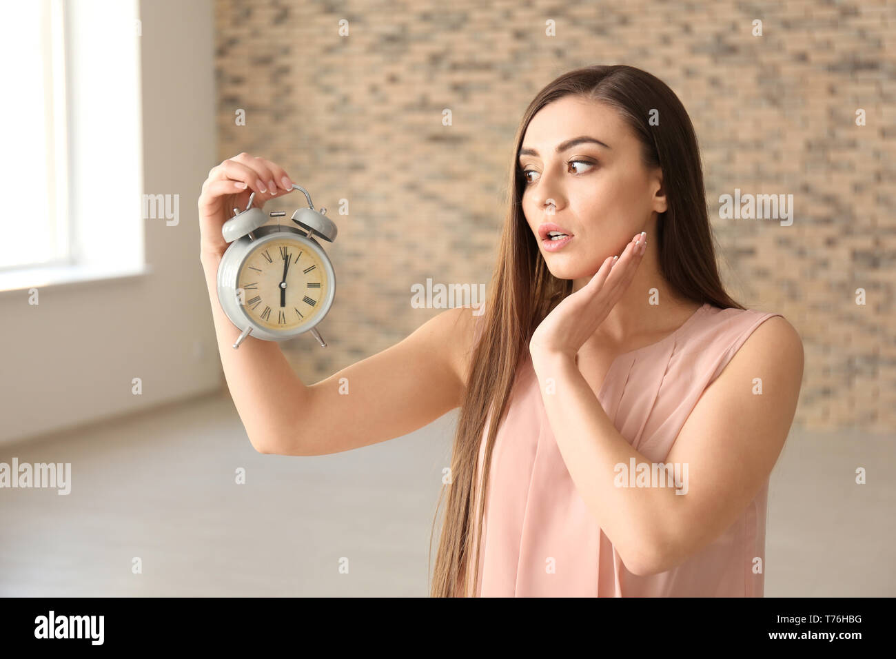 Troubled woman with alarm clock indoors. Time management concept Stock ...