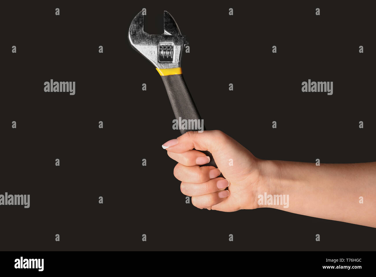 Hand of female car mechanic with adjustable wrench on black background ...