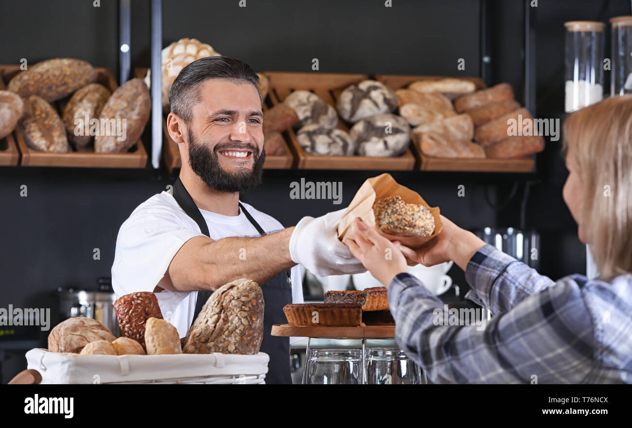 Young man giving fresh bread to woman in bakery Stock Photo - Alamy