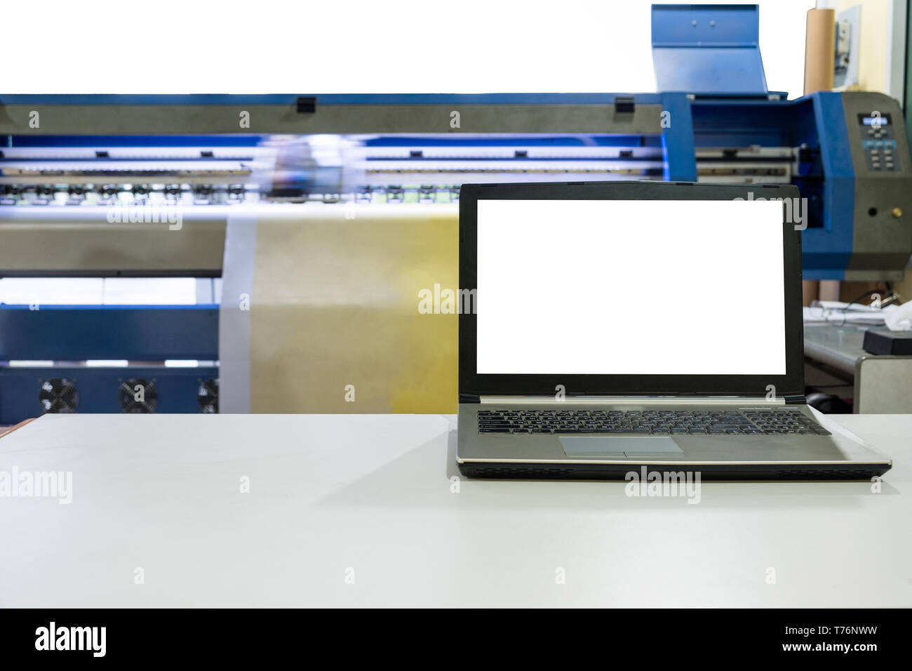 Large inkjet printer working on vinyl banner with notebook screen on ...