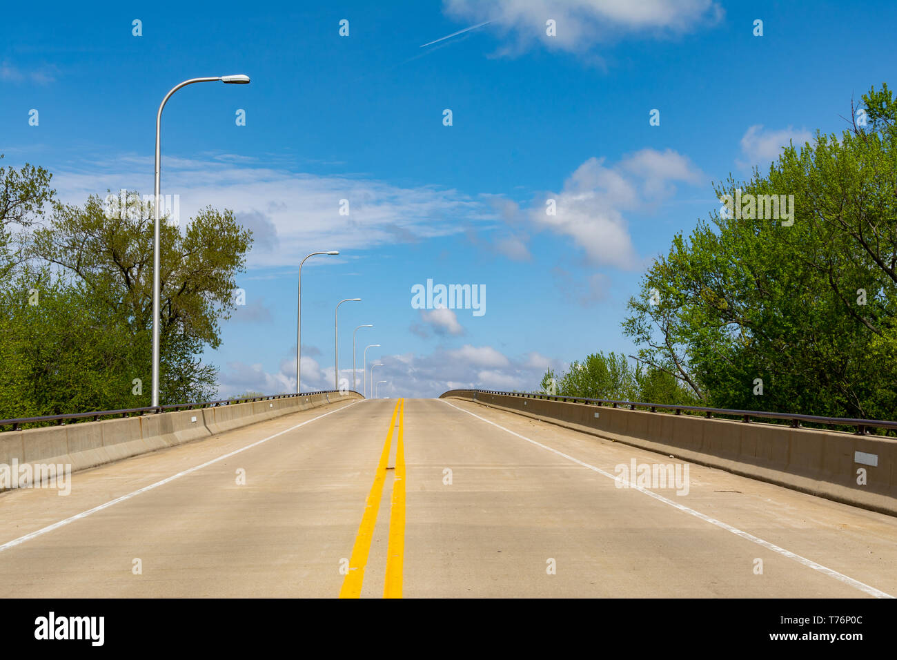 Open two lane road over a bridge with blue skies and clouds above Stock ...