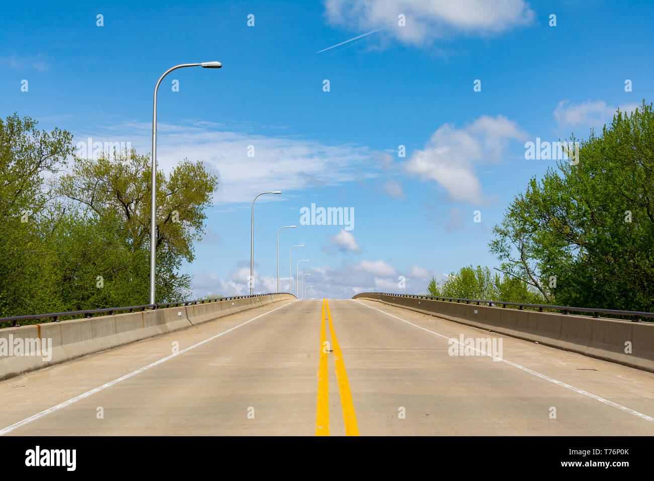 Open two lane road over a bridge with blue skies and clouds above Stock ...
