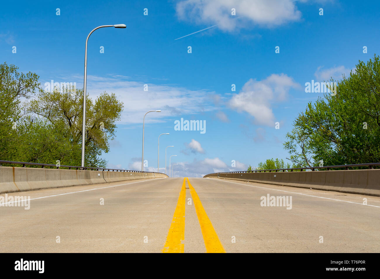 Open two lane road over a bridge with blue skies and clouds above Stock ...