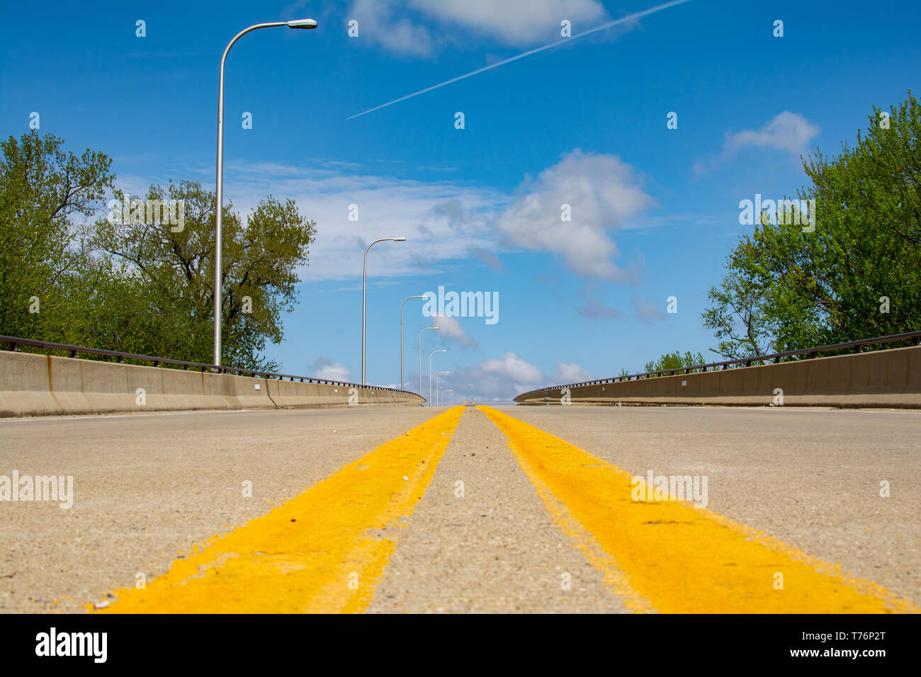 Open two lane road over a bridge with blue skies and clouds above Stock ...