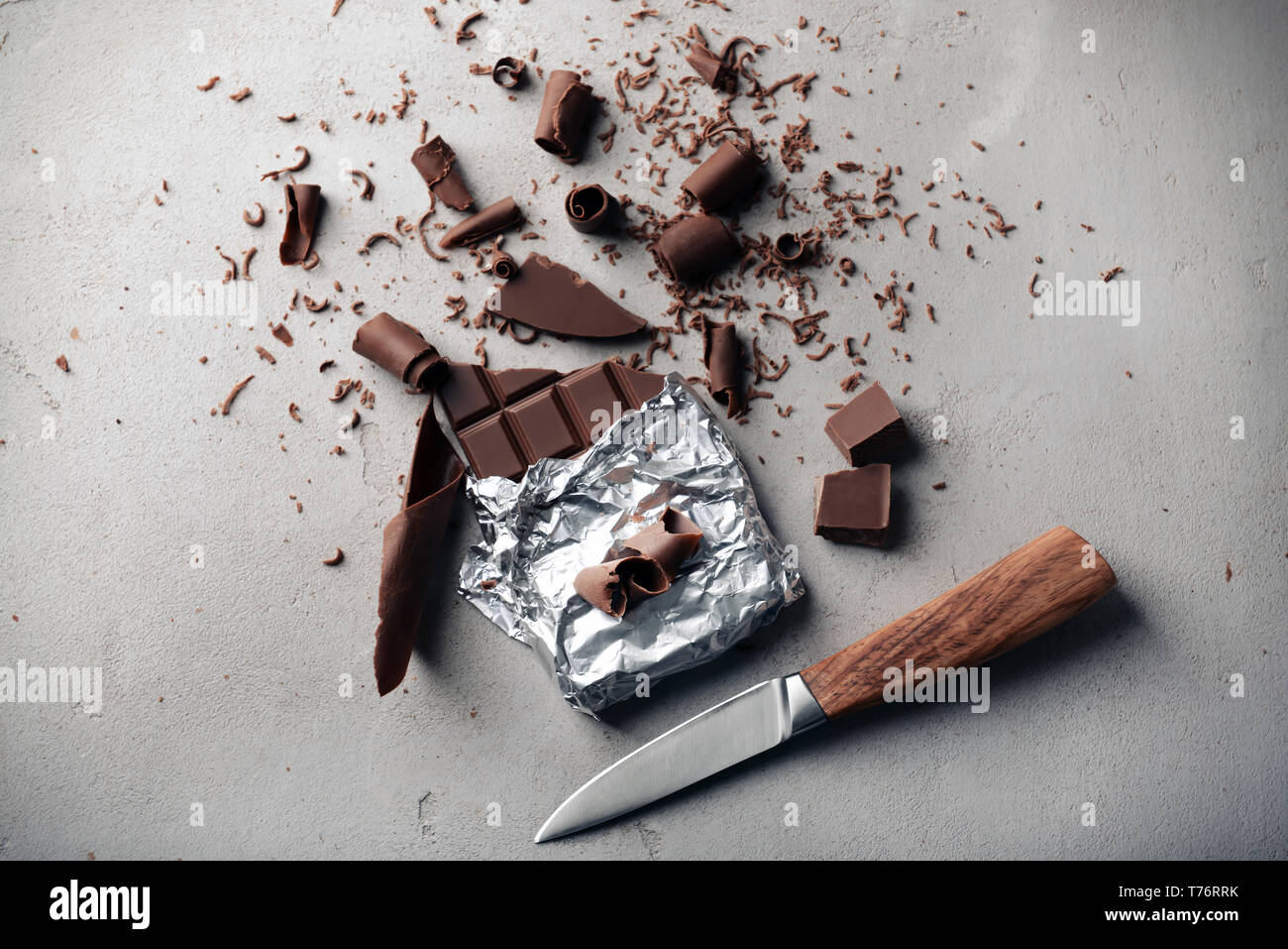 Chocolate bar with curls and knife on grey background Stock Photo - Alamy