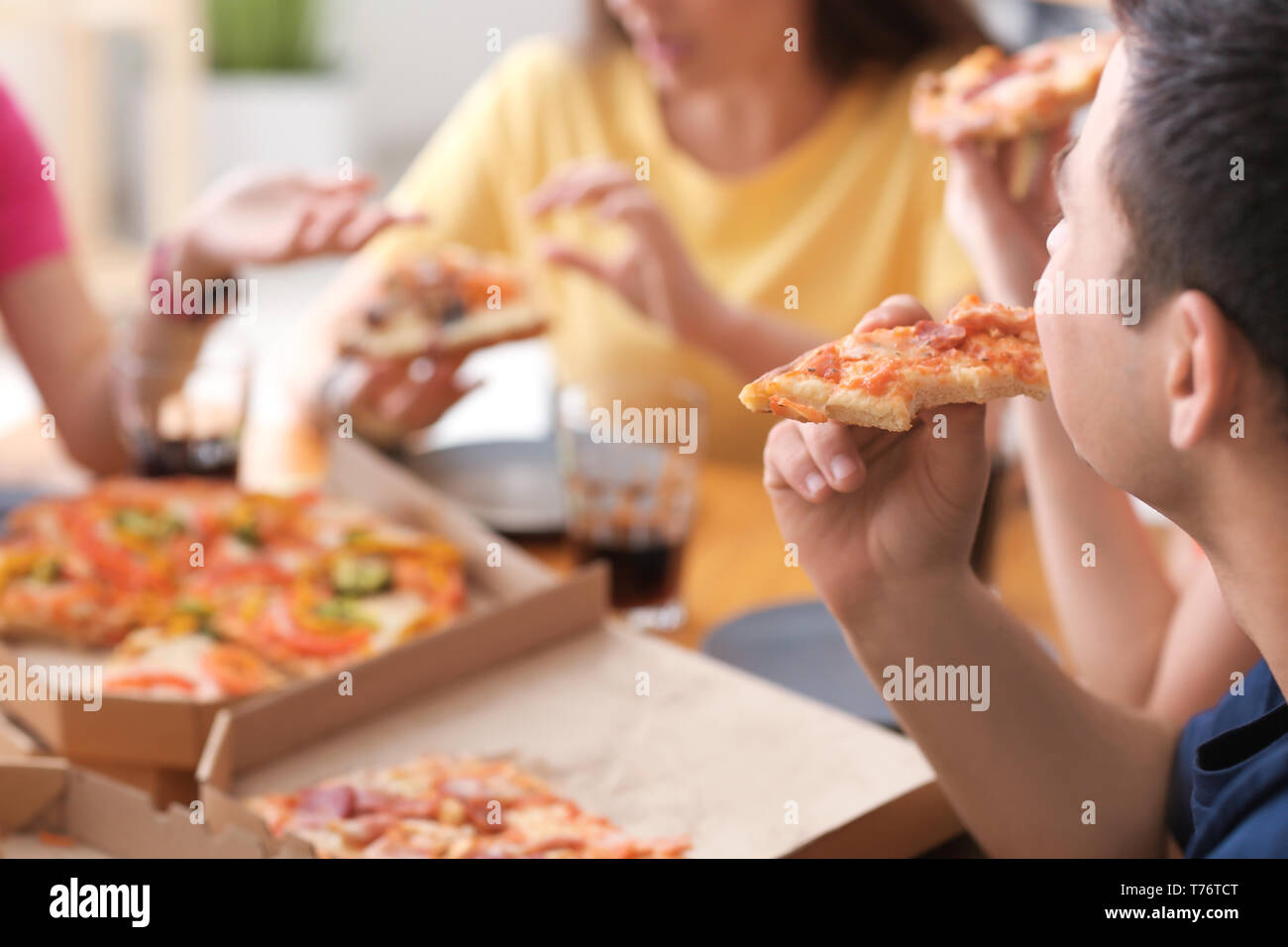 Young people eating pizza at table indoors Stock Photo - Alamy