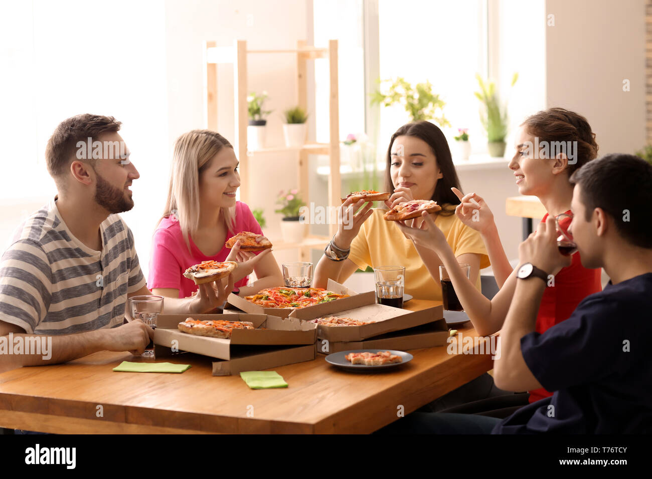 Young people eating pizza at table indoors Stock Photo - Alamy