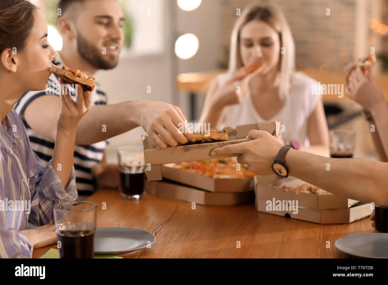Young people eating pizza at table indoors Stock Photo - Alamy