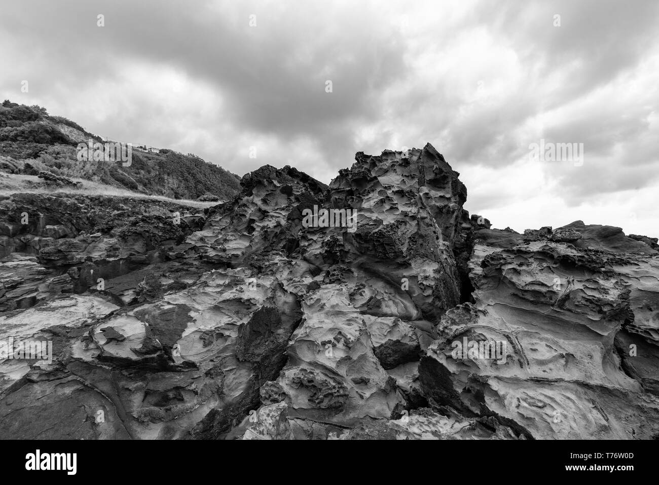Black and white view of dramatic clouds and volcanic rocks in Flores ...