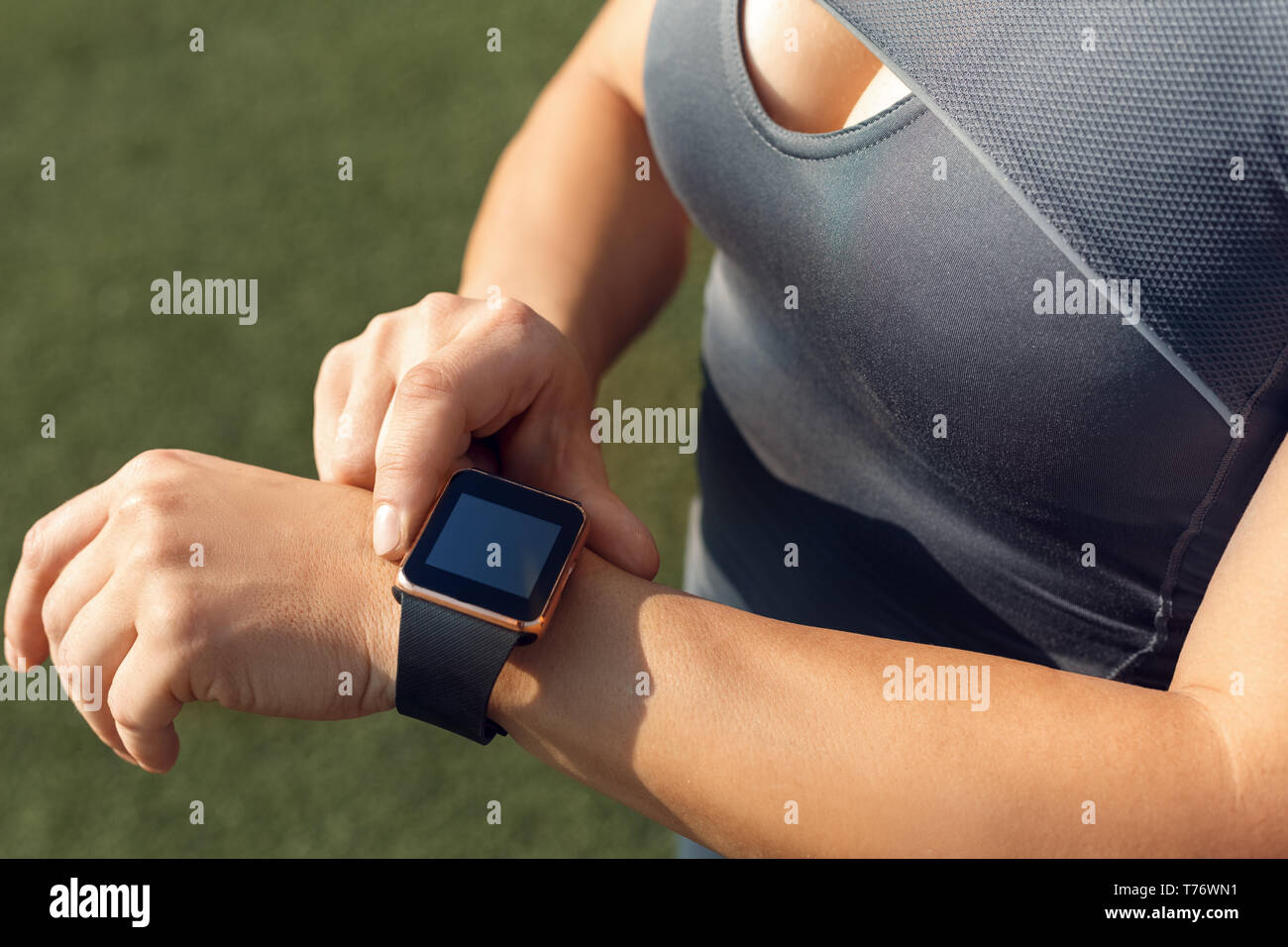 Young woman athlete wearing digital watch standing on stadium sporty ...