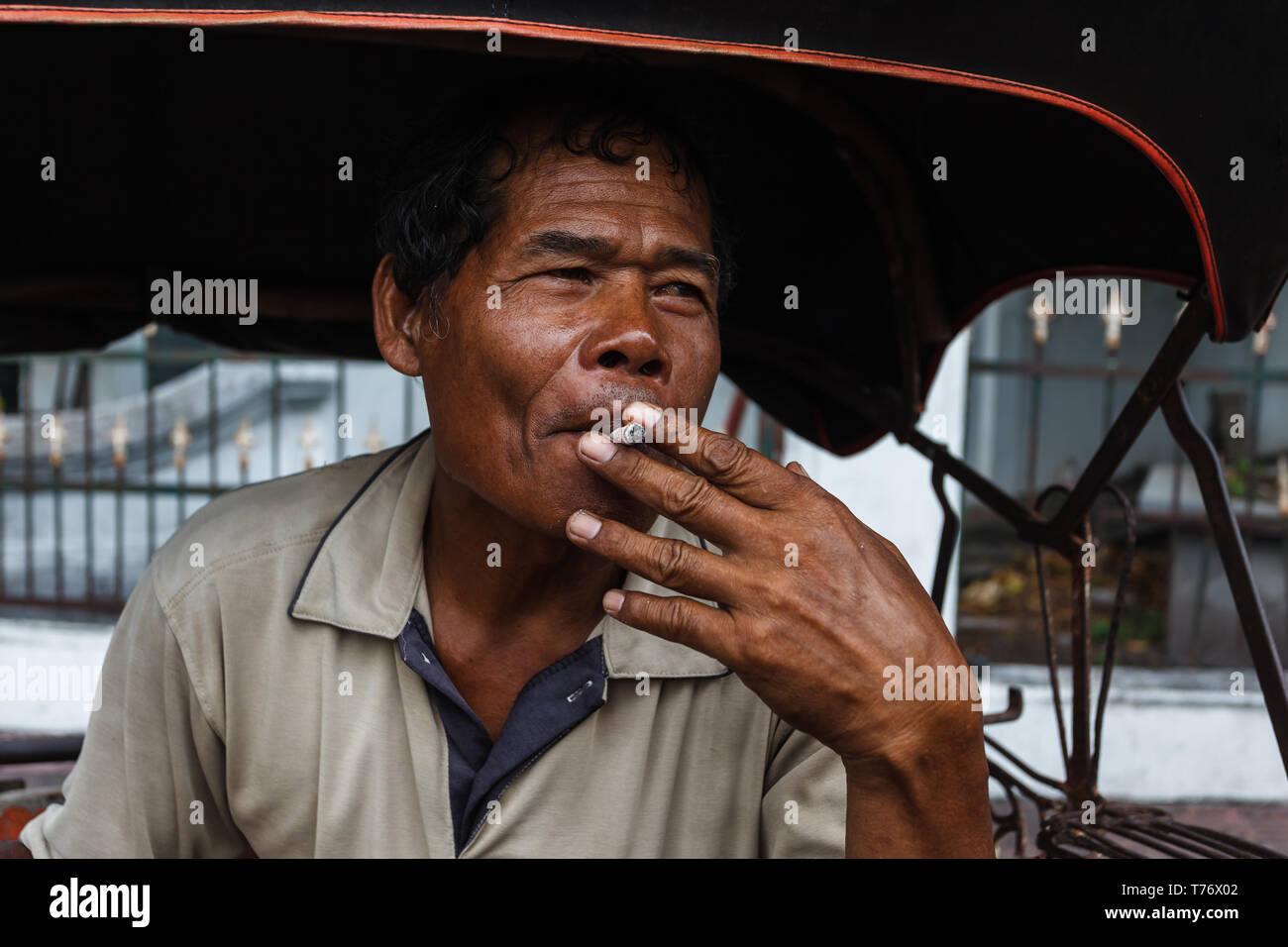 Portrait of driver smoking while waiting for passengers for his bicycle ...