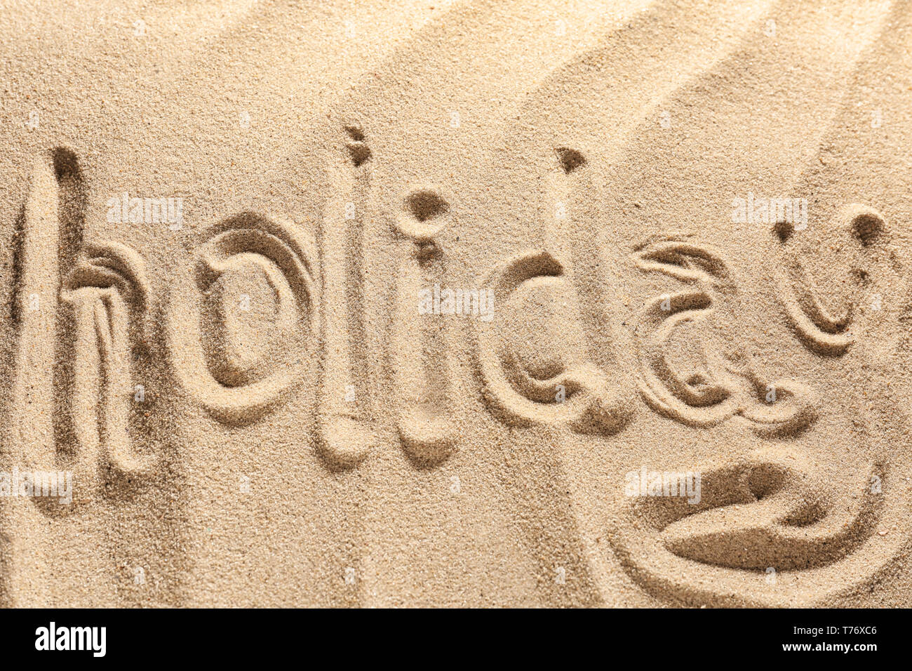 Word HOLIDAY written on beach sand Stock Photo - Alamy
