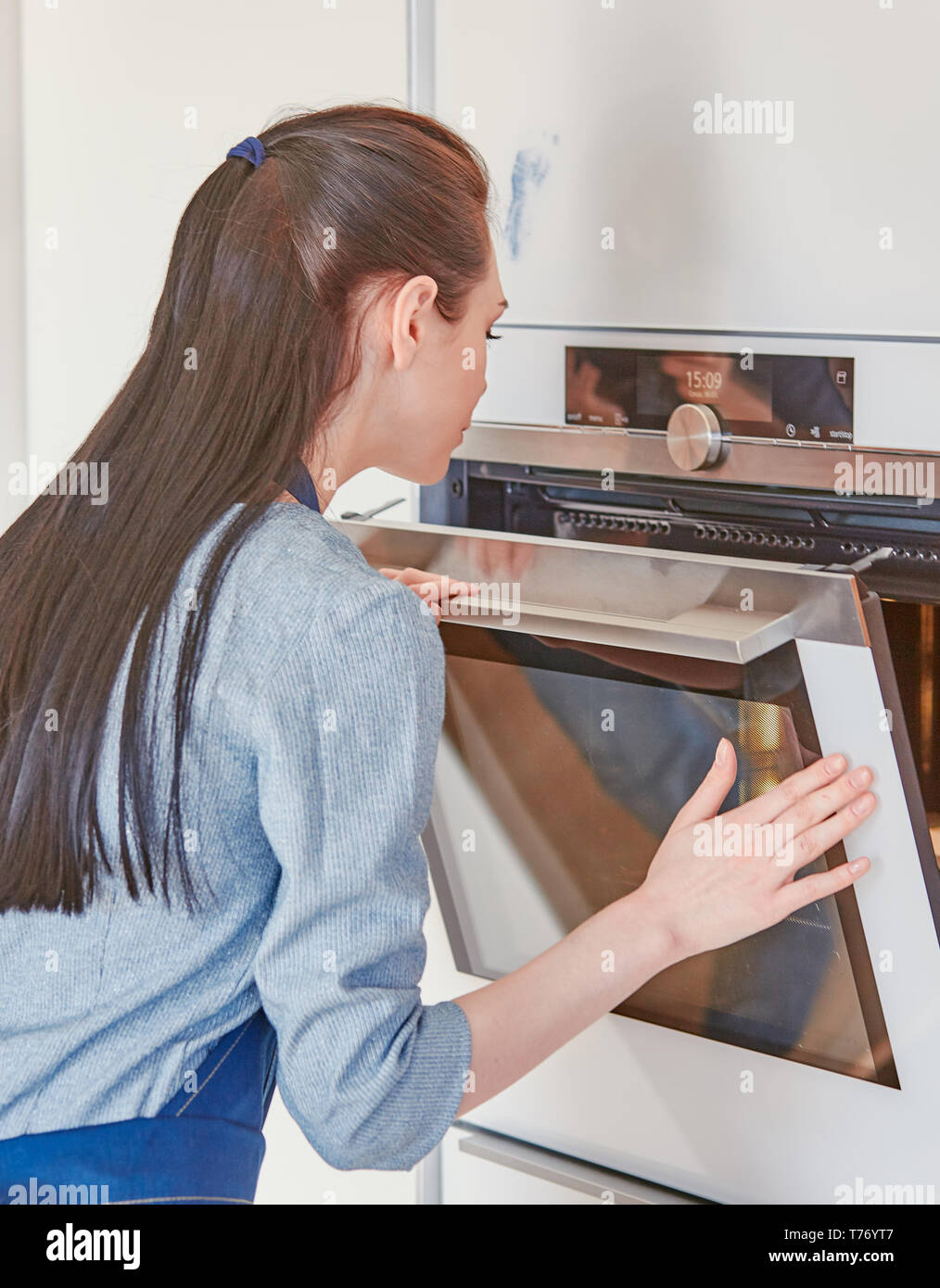 Beautiful woman in the kitchen, waiting with the front of the oven ...