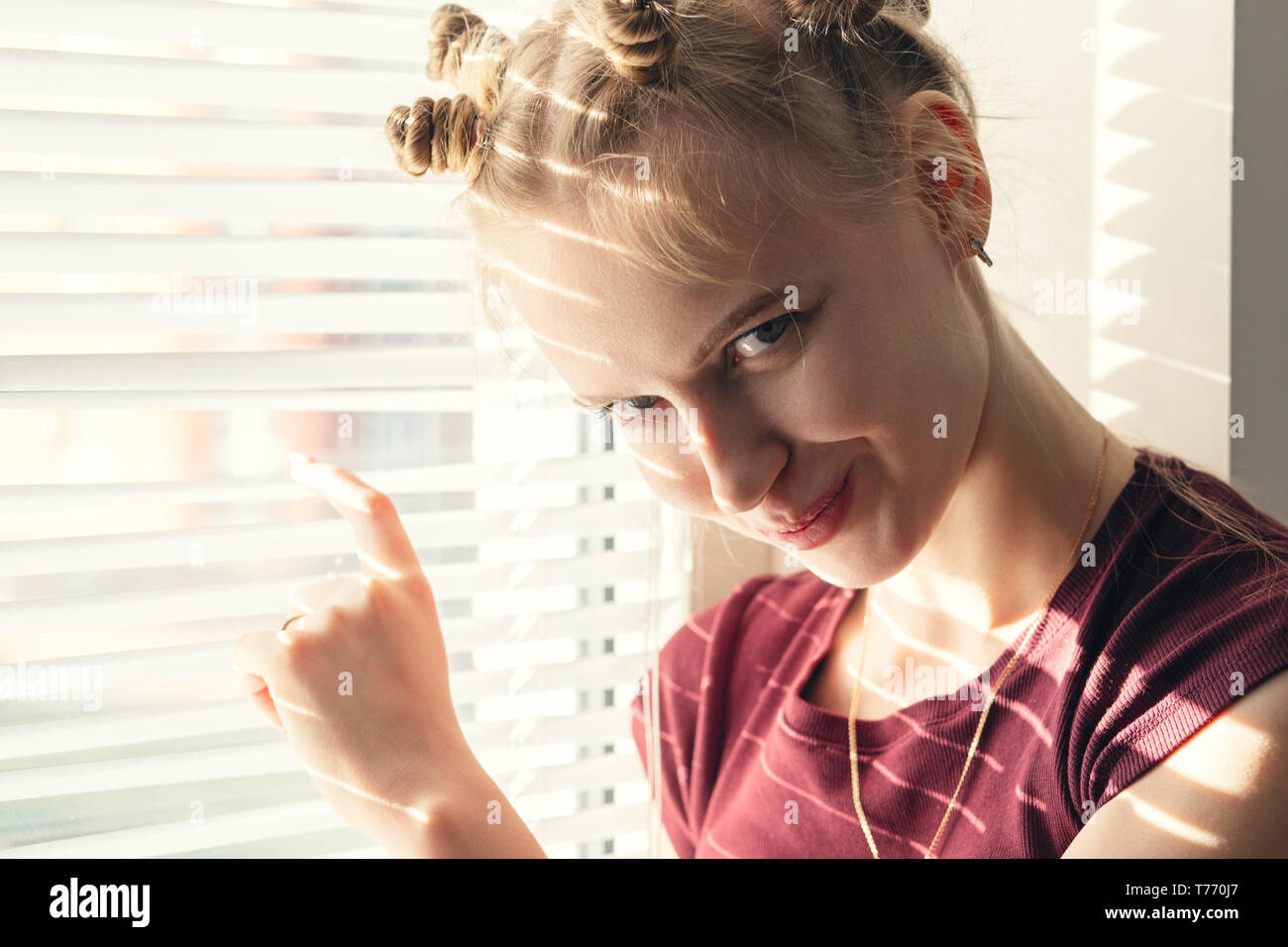 fun shy young woman near window blinds looking at camera smiling Stock ...