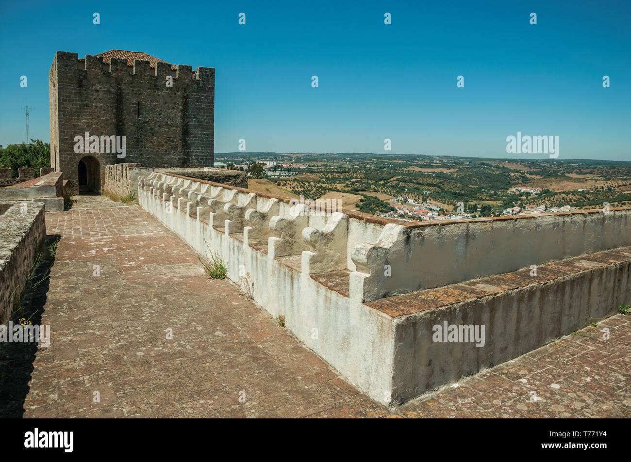 Pathway on top of stone wall with tower and merlons in sunny day at the ...