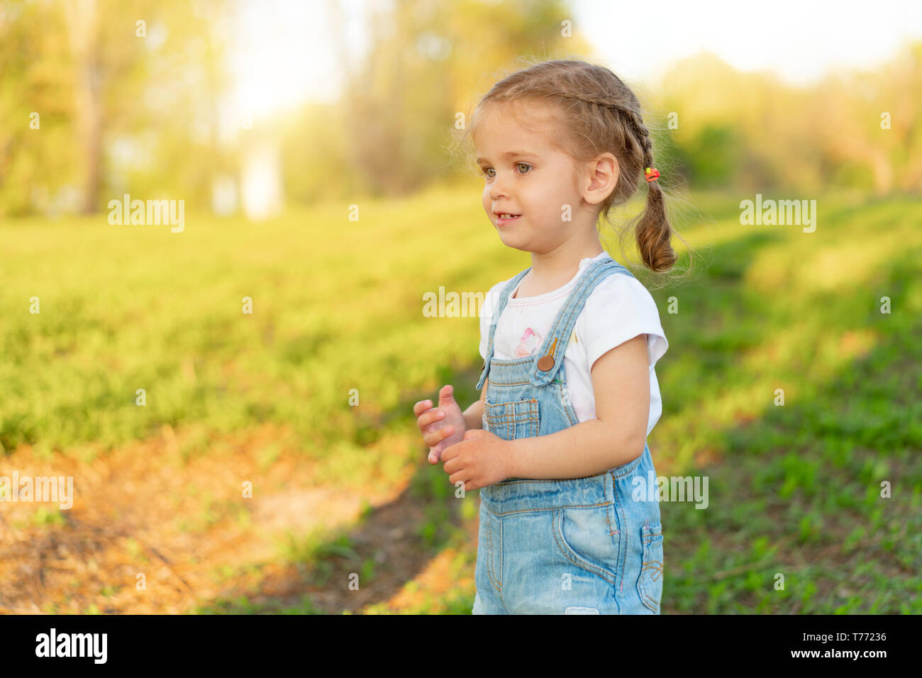 Summer season. Little Caucasian girl walks on nature dressed in denim ...