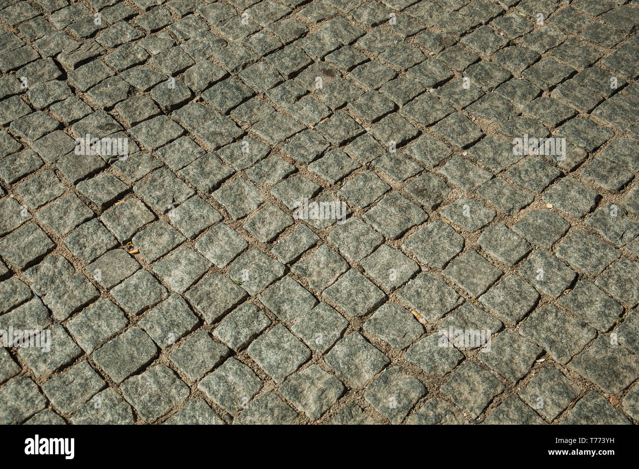 Pavement made of granite setts on alley, forming a singular background ...