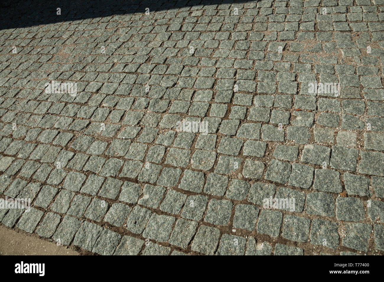 Pavement made of granite setts on alley, forming a singular background ...