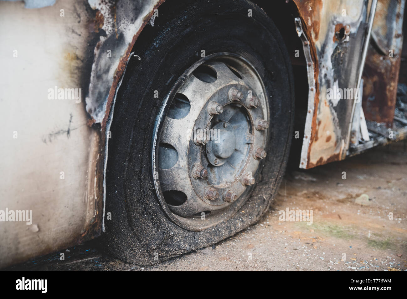 Burned down bus, view from outside, damaged walls and flat tire Stock ...